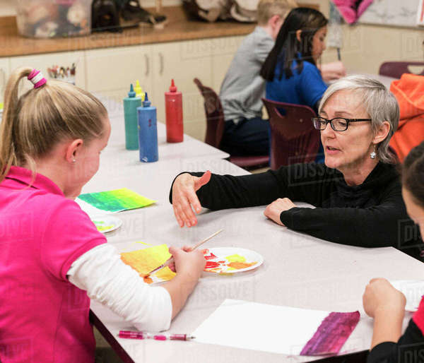 Teacher talking to student painting in art class - Stock Photo - Dissolve
