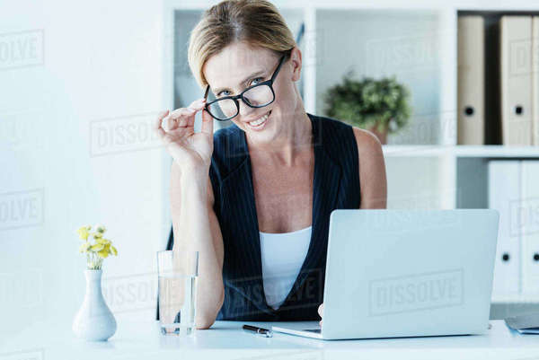 Portrait Of Smiling Businesswoman In Eyeglasses Looking At Camera While