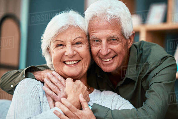 Portrait, senior couple and hug in living room, family home and relaxing in lounge for love ...
