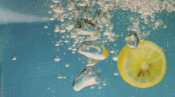 Underwater lemon slice in soda water or lemonade with bubbles. Refreshing soda tonic fizzy ...