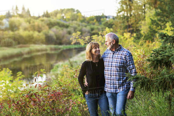 A Mature Couple Enjoying Quality Time Together While Walking In A City Park On A Warm Fall