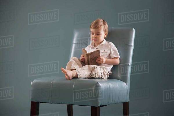 Toddler Sitting In A Big Chair Reading A Book; Jordan, Ontario, Canada ...