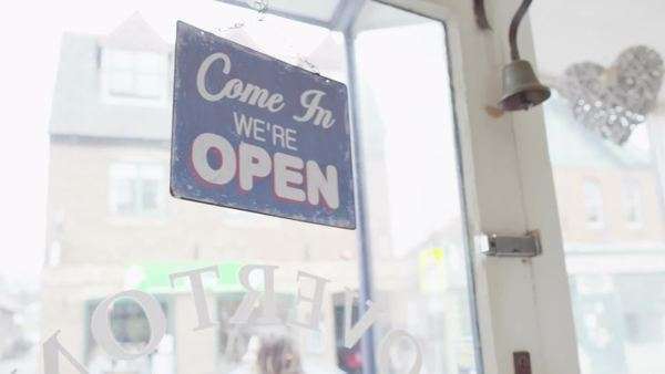 Shopkeeper turns the 'Closed' sign to 'Open' in his storefront window ...