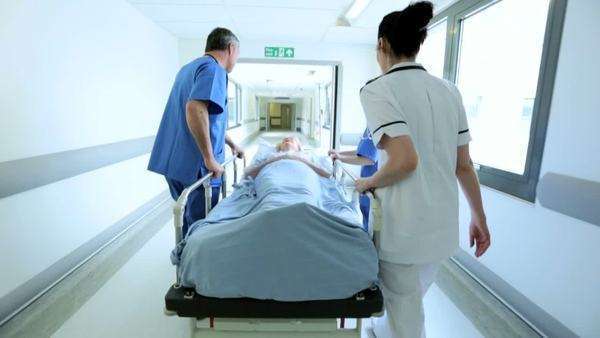 Dedicated Caucasian medical staff moving patient on hospital bed ...