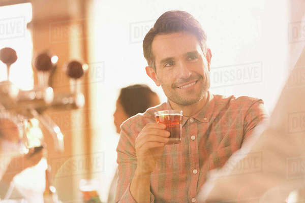 Smiling man drinking cocktail at bar - Royalty-free Stock Photo | Dissolve
