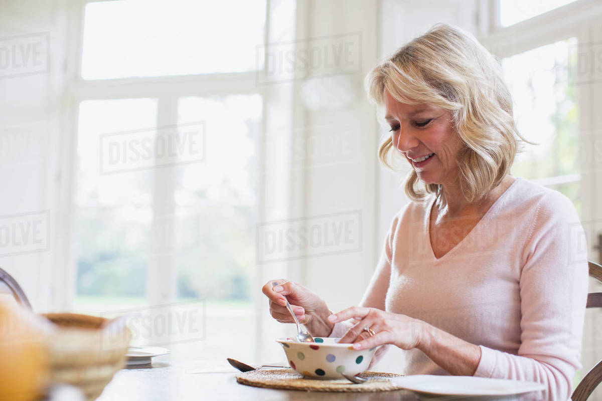 Smiling mature woman eating breakfast - Stock Photo - Dissolve