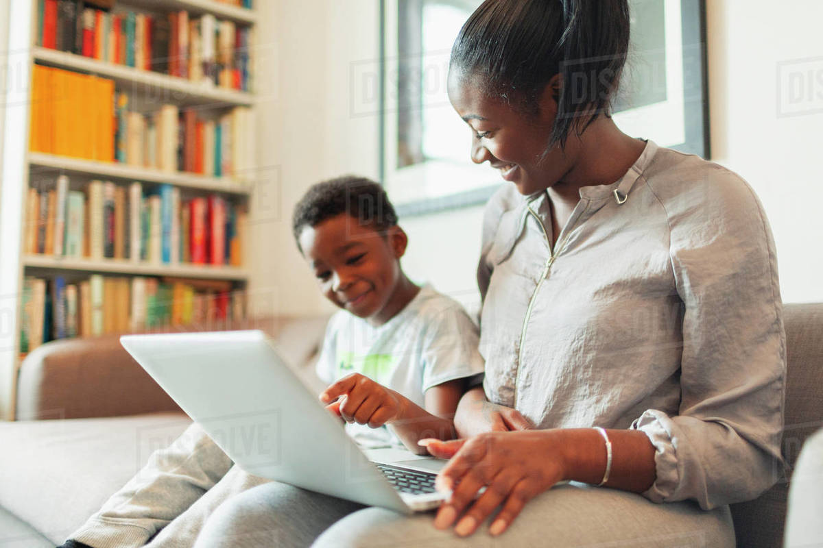 Mother and son using laptop on living room sofa - Royalty-free Stock ...