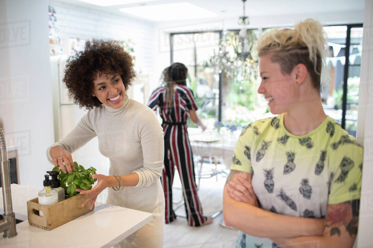 Happy young women talking in kitchen - Royalty-free Stock Photo | Dissolve