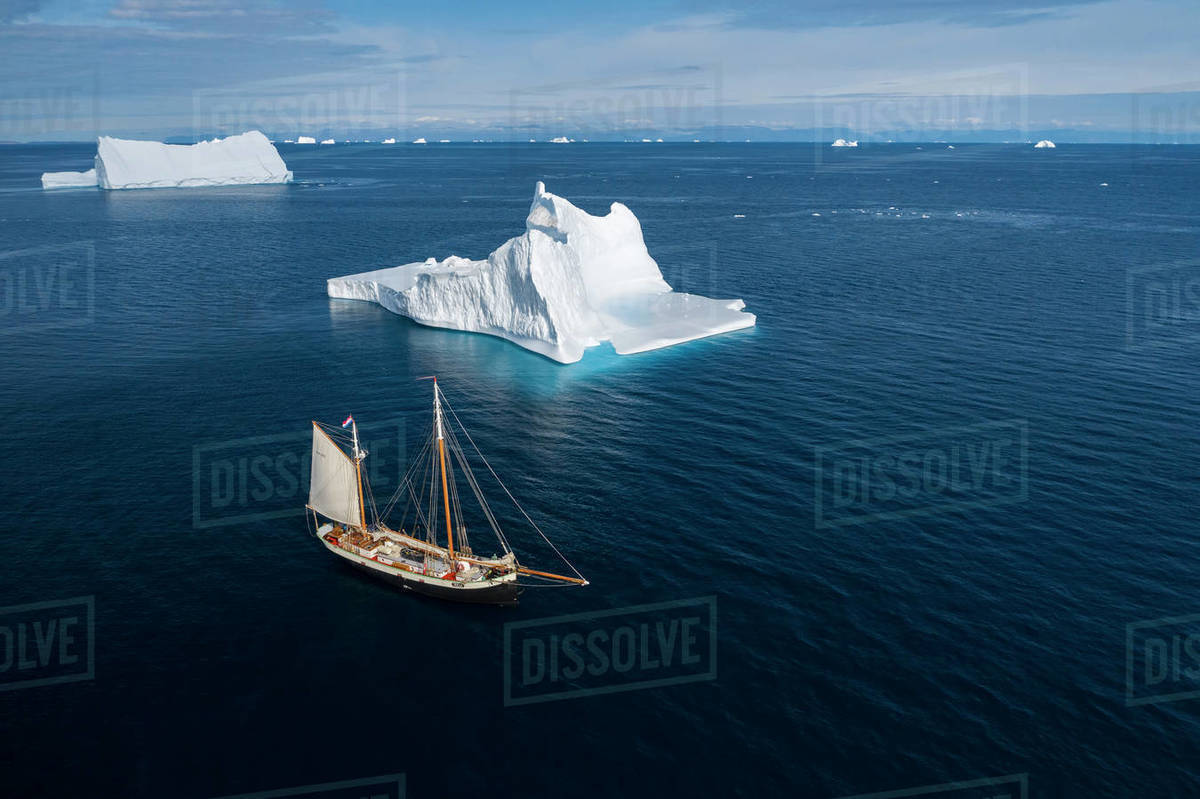 Ship sailing past majestic icebergs on sunny blue Atlantic Ocean ...