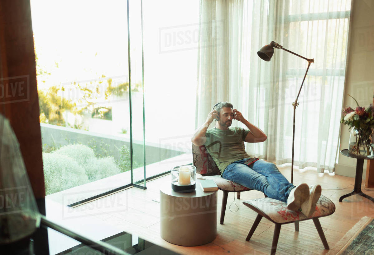 Man Relaxing Listening To Music With Headphones In Living Room Stock