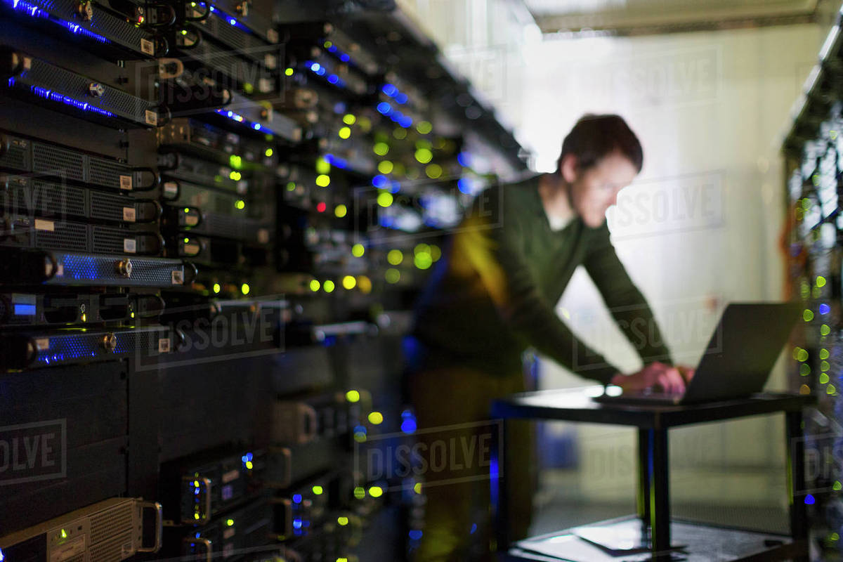 Server room technician working at laptop in corridor - Royalty-free ...