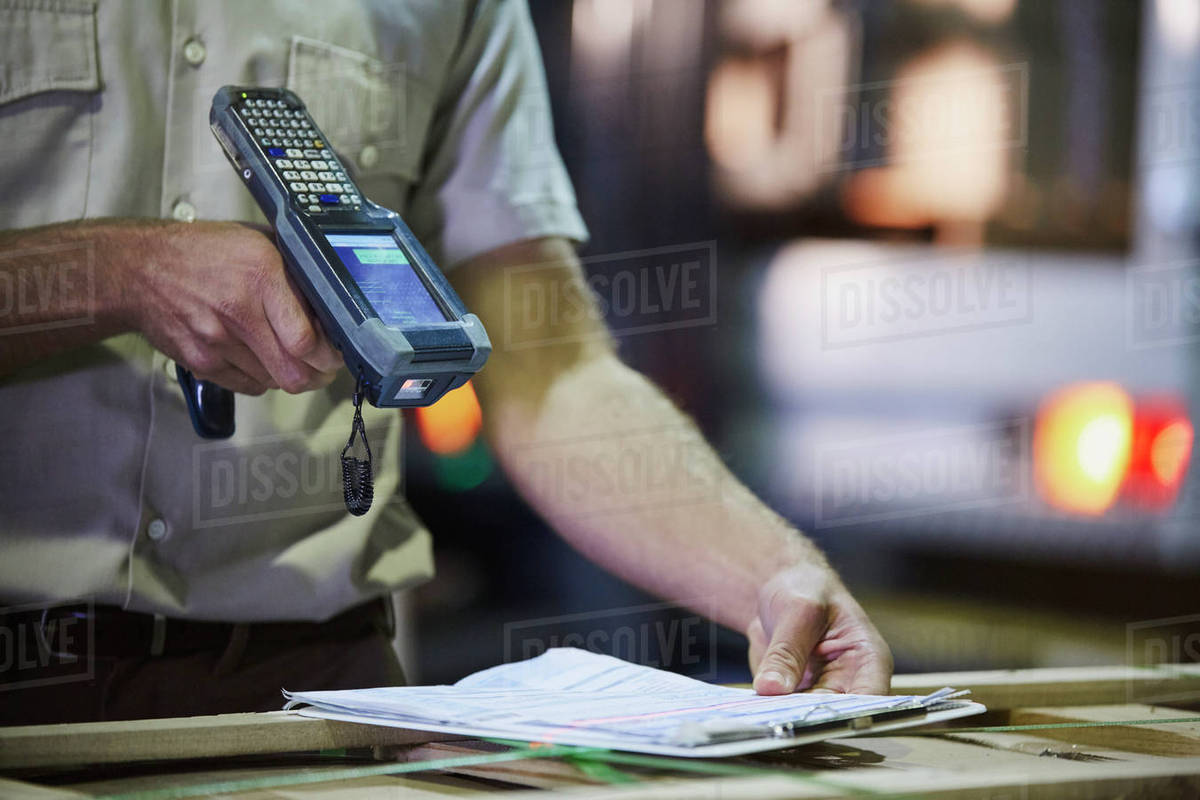 Worker with scanner scanning paperwork in distribution warehouse ...