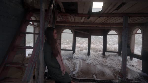 Female in vintage abandoned home room sinking in tidal water on sandy ...