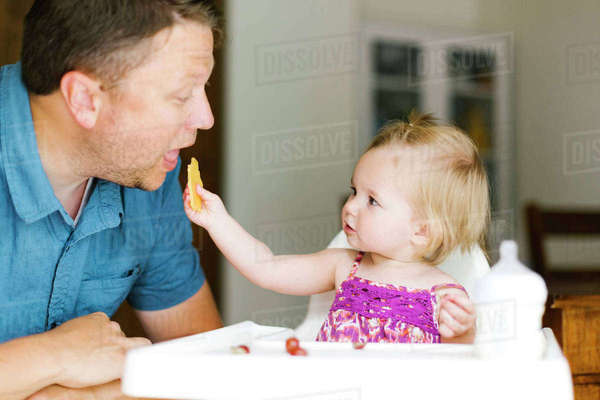Baby girl feeding her father - Royalty-free Stock Photo | Dissolve