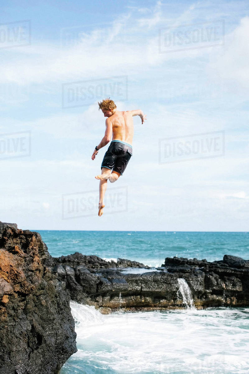 Young man jumping into sea - Royalty-free Stock Photo | Dissolve