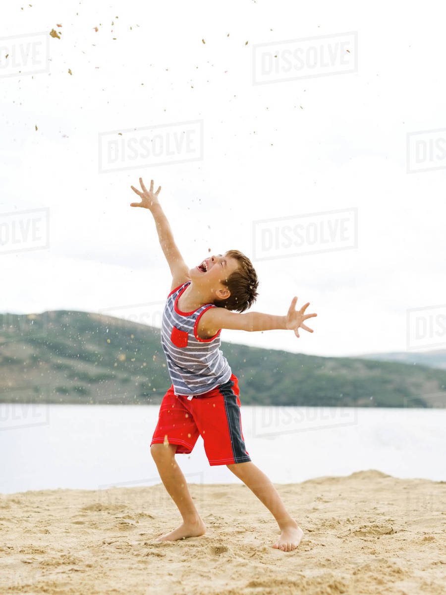 Boy playing on beach by lake - Royalty-free Stock Photo | Dissolve