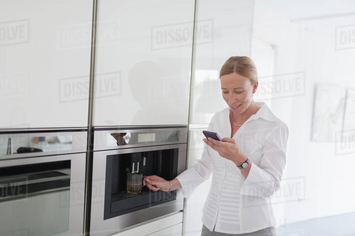 Woman using phone in kitchen - Royalty-free Stock Photo | Dissolve