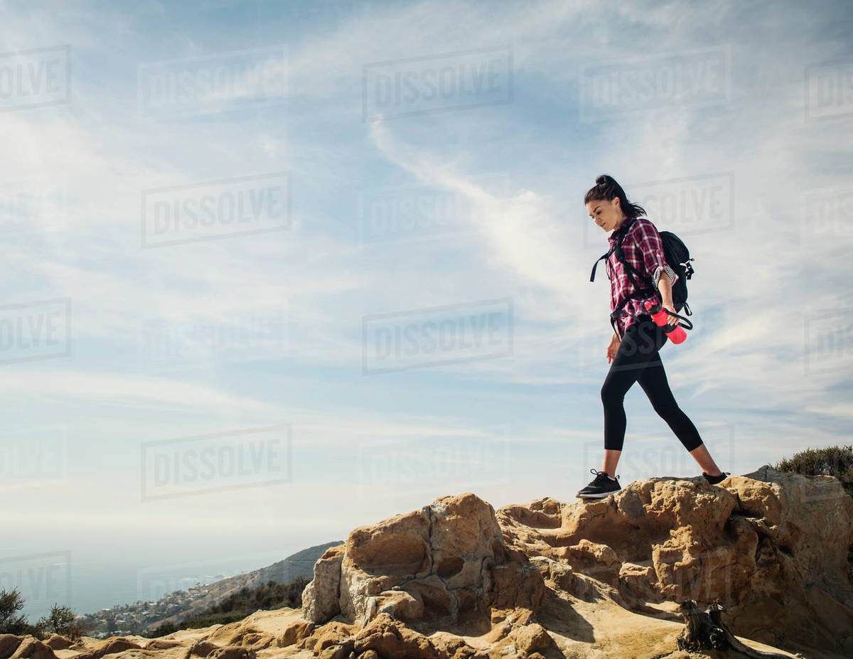 Woman hiking over rocks - Stock Photo - Dissolve