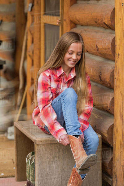 Girl putting on cowboy boots - Royalty-free Stock Photo | Dissolve