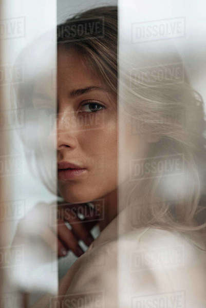 Portrait of young woman behind window - Stock Photo - Dissolve
