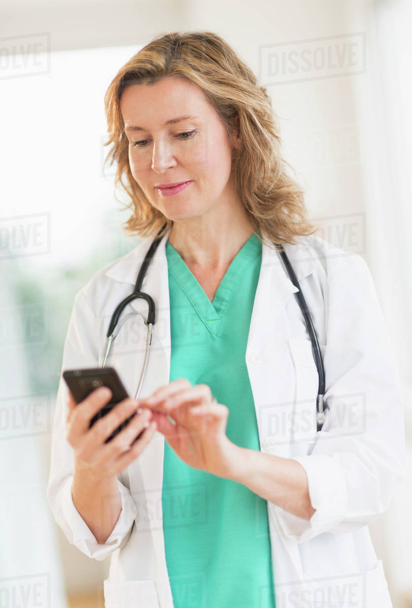 Female doctor using phone - Royalty-free Stock Photo | Dissolve