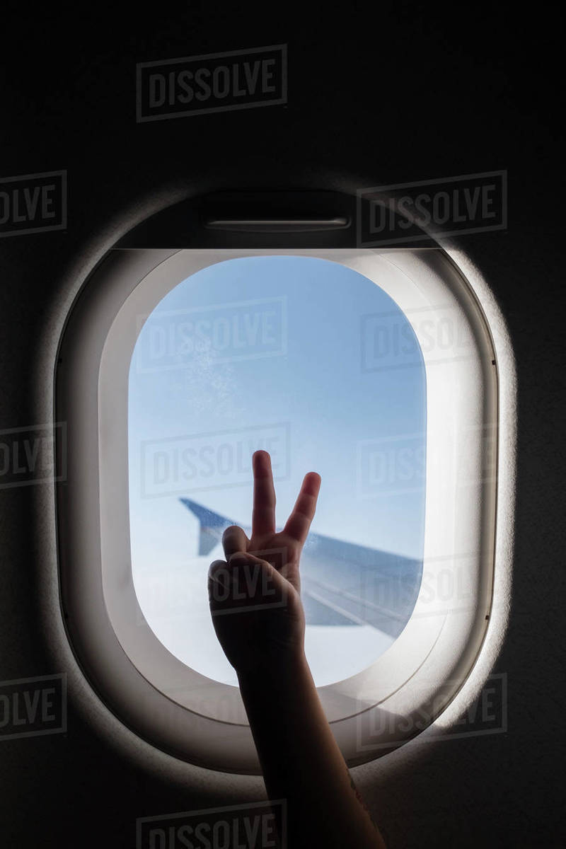 Silhouette of girl's hand doing peace sign by airplane window - Stock ...