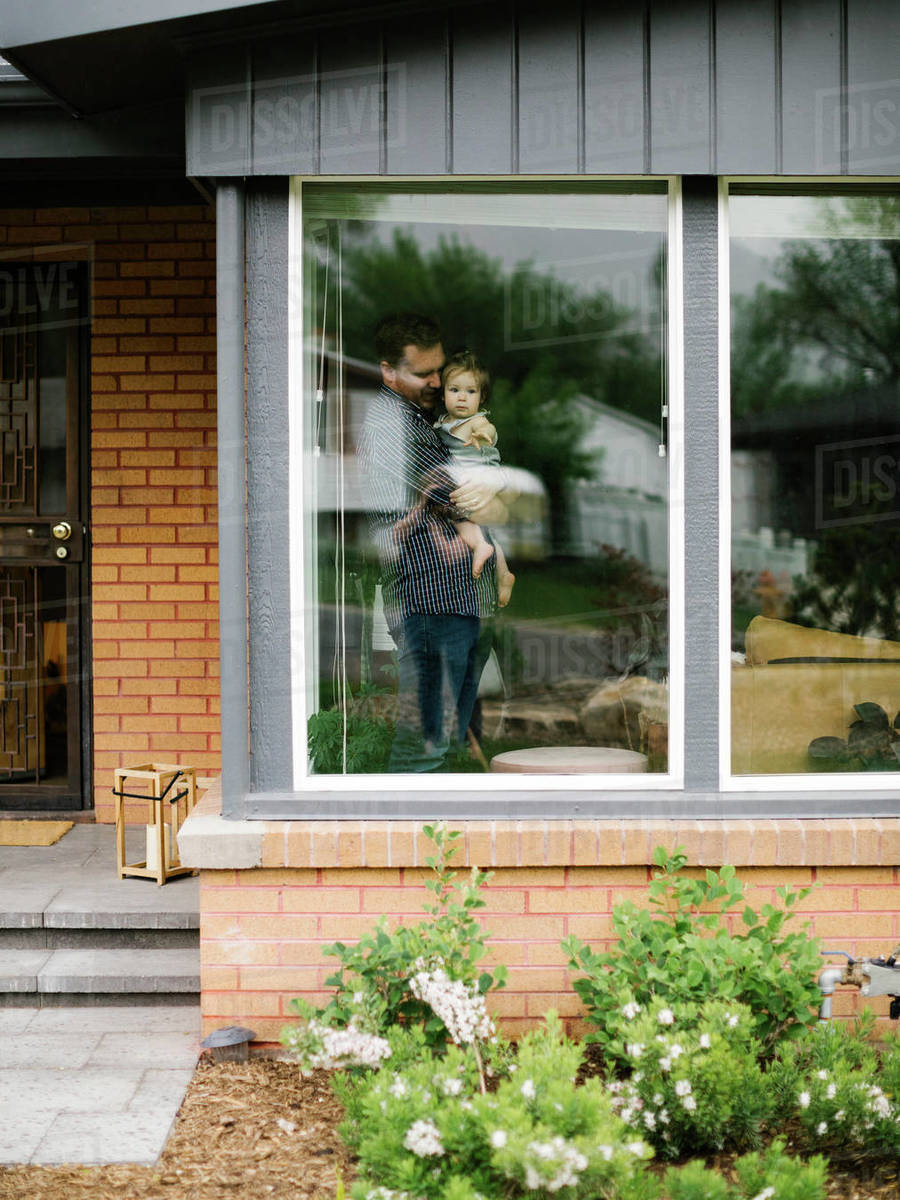 Father holding his daughter behind window of house - Royalty-free Stock ...