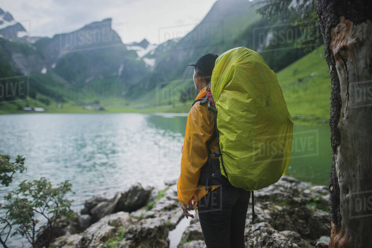 Woman wearing yellow backpack by Seealpsee lake in Appenzell Alps ...