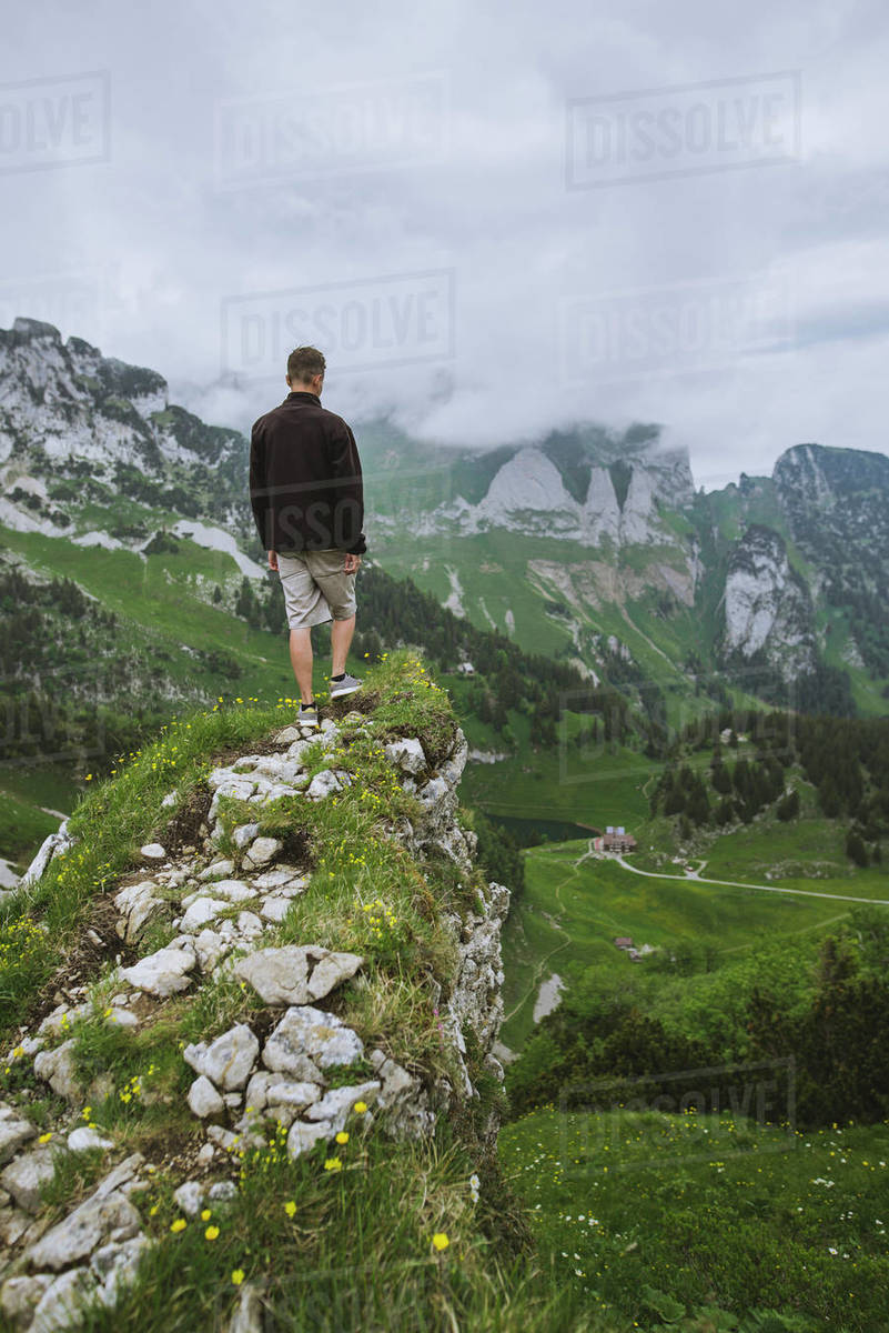 Man on rock by mountains - Stock Photo - Dissolve