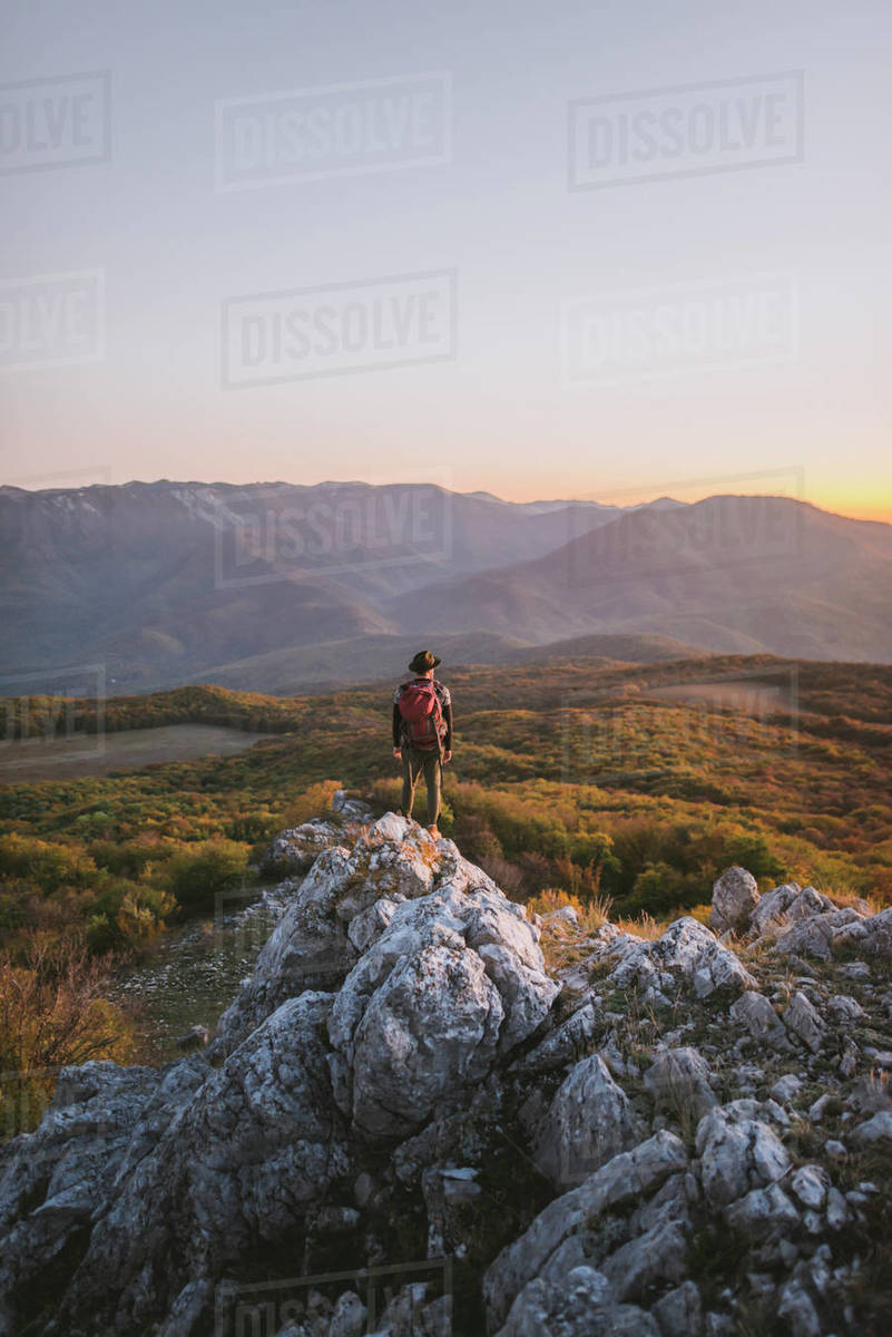 Man on rock by mountains at sunset - Stock Photo - Dissolve