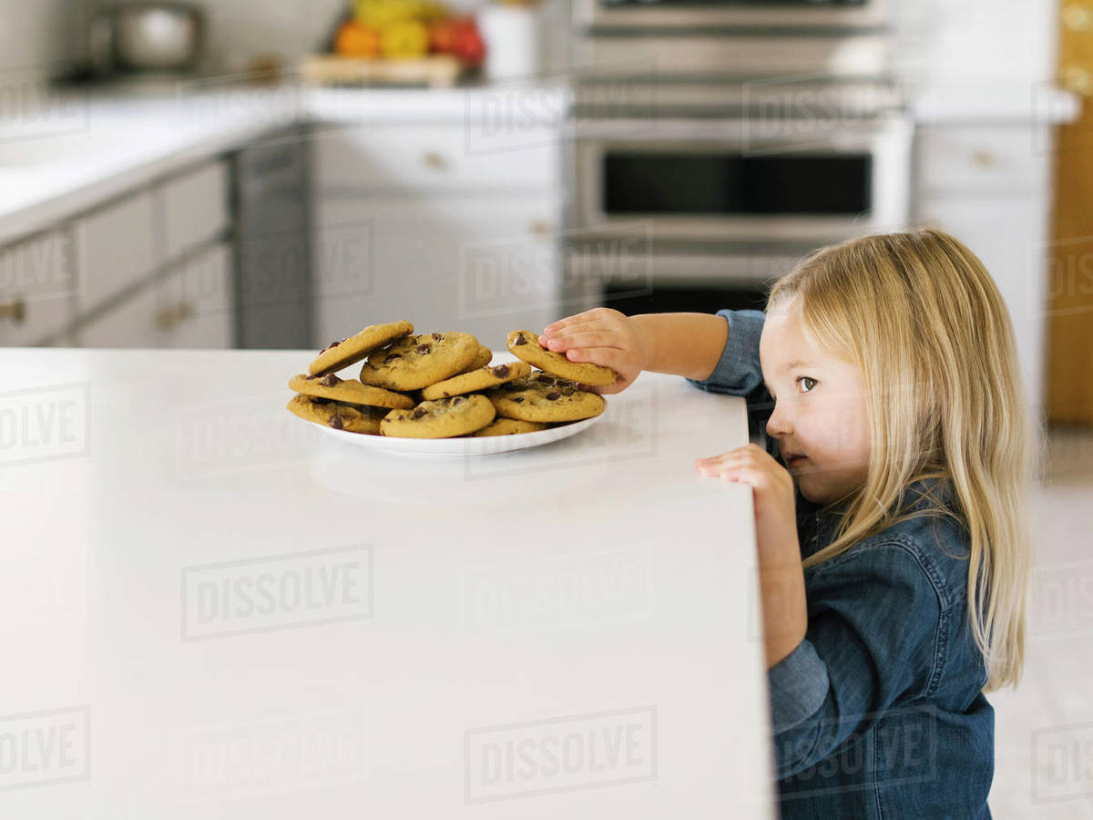 Girl stealing chocolate chip cookie - Royalty-free Stock Photo | Dissolve
