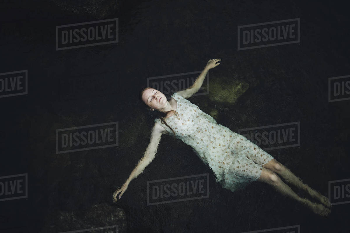 Young woman floating in water - Stock Photo - Dissolve