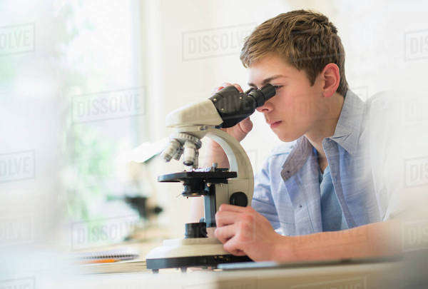 Teenage boy (16-17) looking through microscope - Royalty-free Stock ...