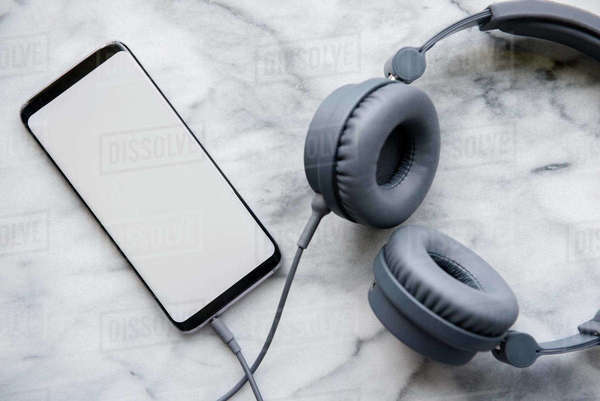 Black headphones connected to smart phone - Stock Photo - Dissolve