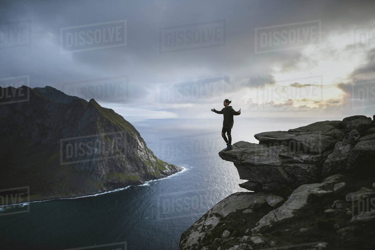 Man standing on cliff at Ryten mountain in Lofoten Islands, Norway ...