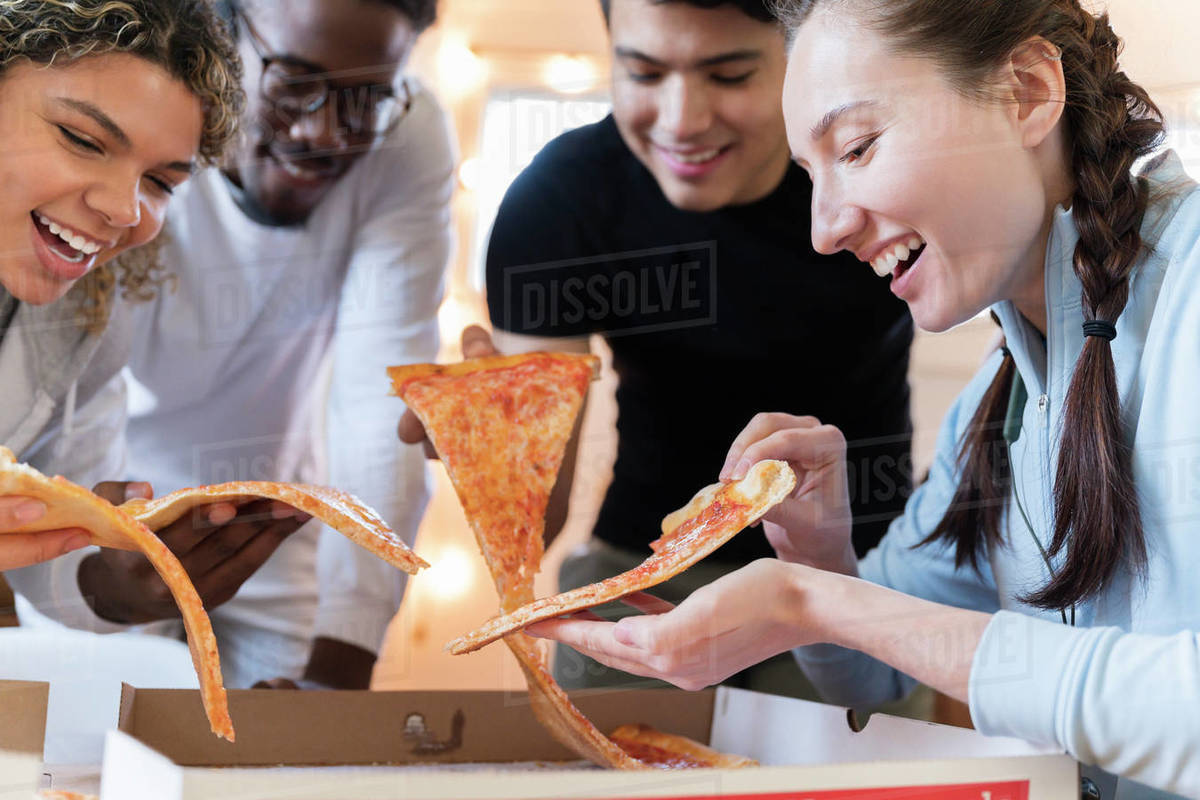 Group of friends having pizza together - Stock Photo - Dissolve
