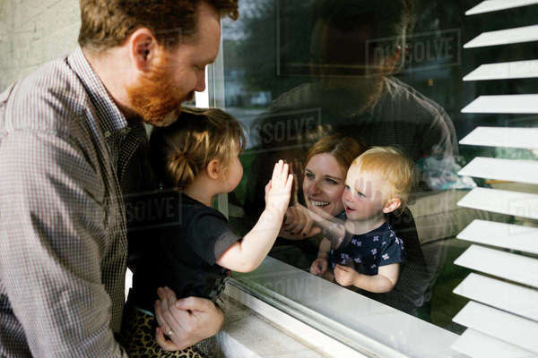 Family with daughters (2-3) visiting through window - Stock Photo ...