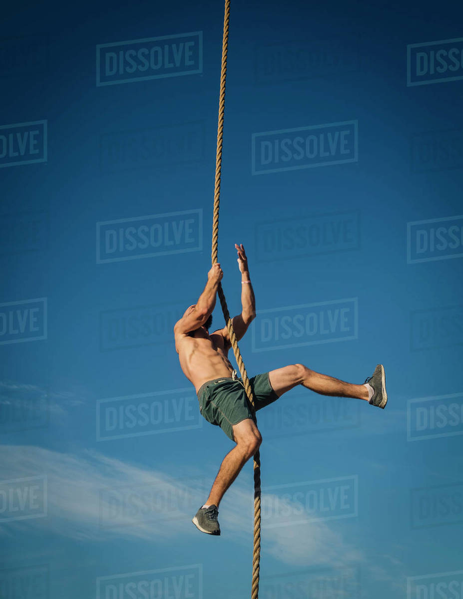 Man climbing on rope - Stock Photo - Dissolve