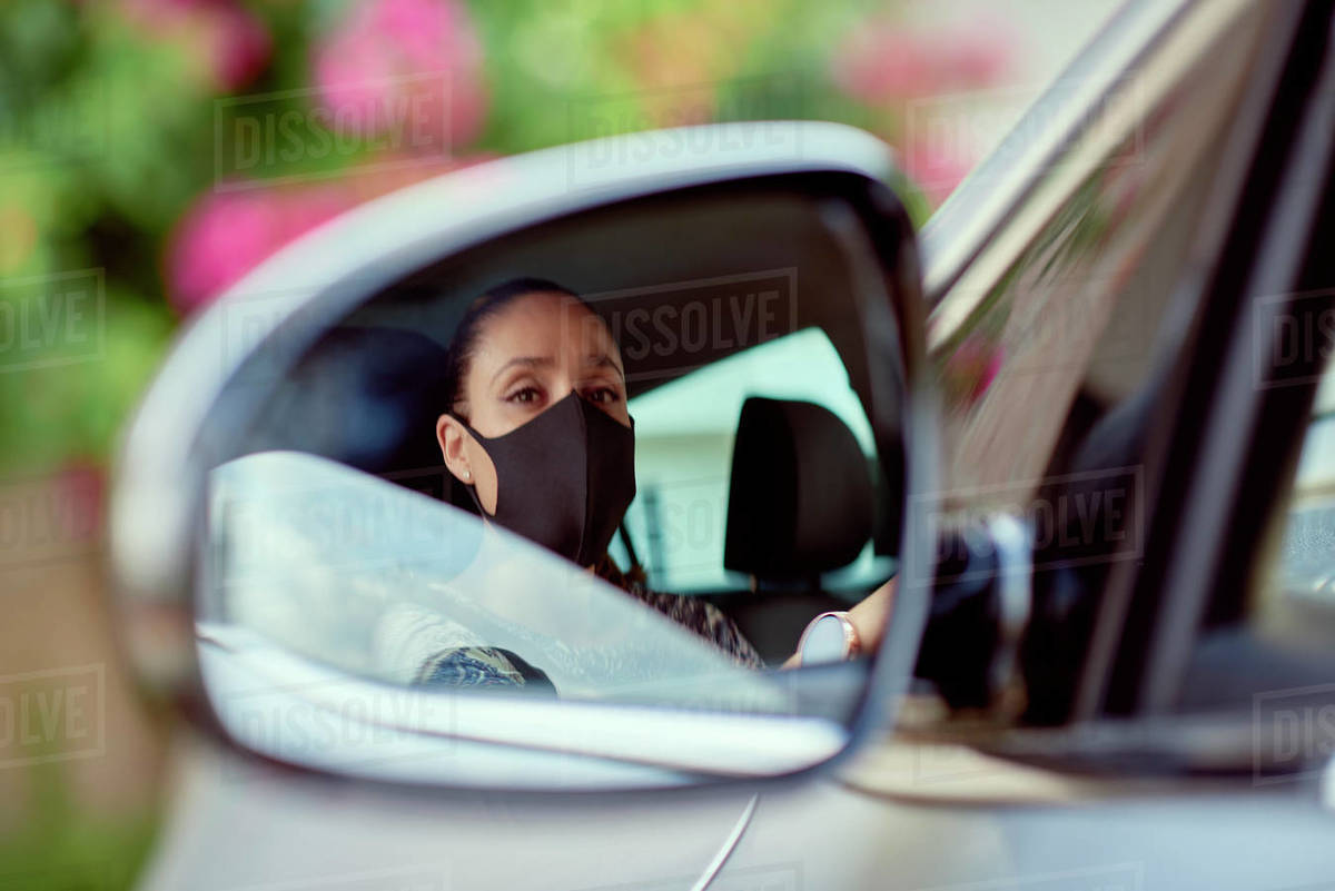 Woman with face mask driving car reflected in mirror - Stock Photo ...