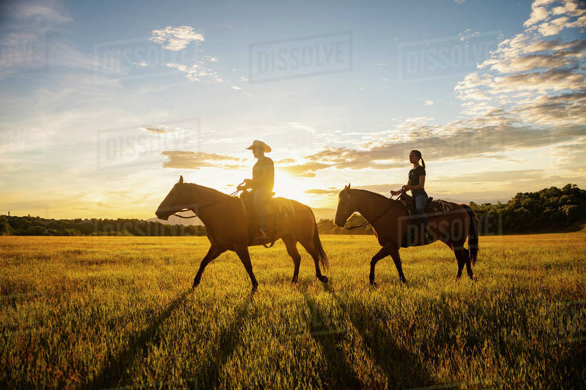USA, Utah, Salem, Father and daughter (14-15) riding horses at sunset ...