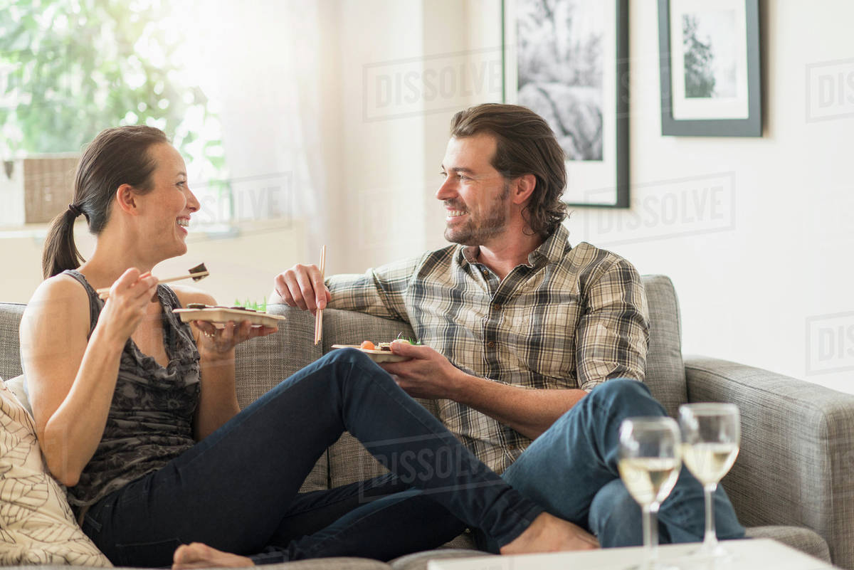 Cheerful couple eating on sofa - Royalty-free Stock Photo | Dissolve