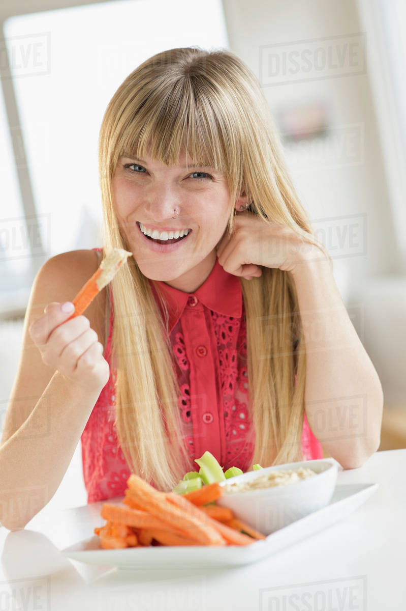 Portrait of woman eating carrots - Royalty-free Stock Photo | Dissolve
