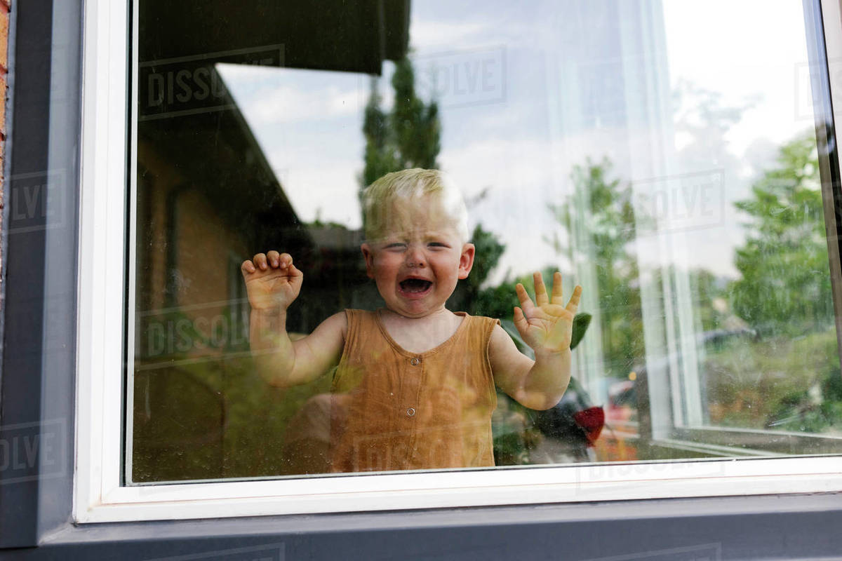 Baby boy, 18-23 months standing behind window and crying - Royalty-free ...