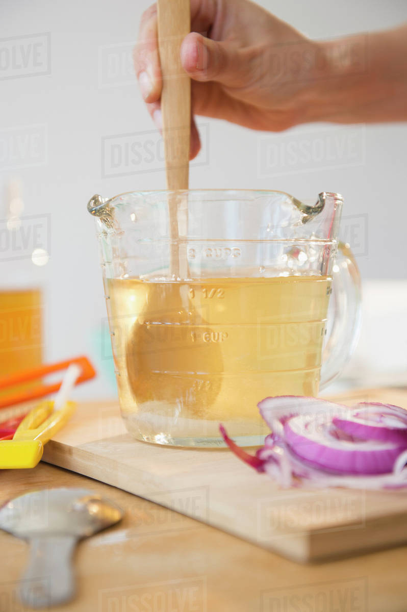 Studio shot of woman's hand stirring liquid in jug - Stock Photo - Dissolve