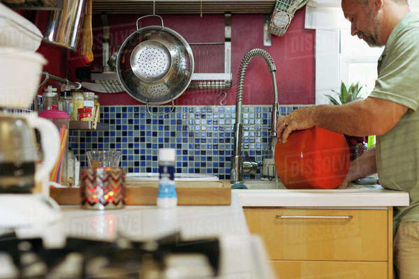 Man washing red pot - Royalty-free Stock Photo | Dissolve