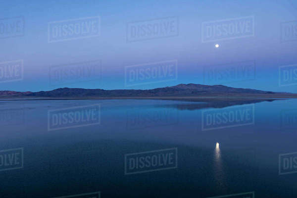 USA, Nevada, Hawthorne, Calm Walker Lake reflecting Moon at dusk ...