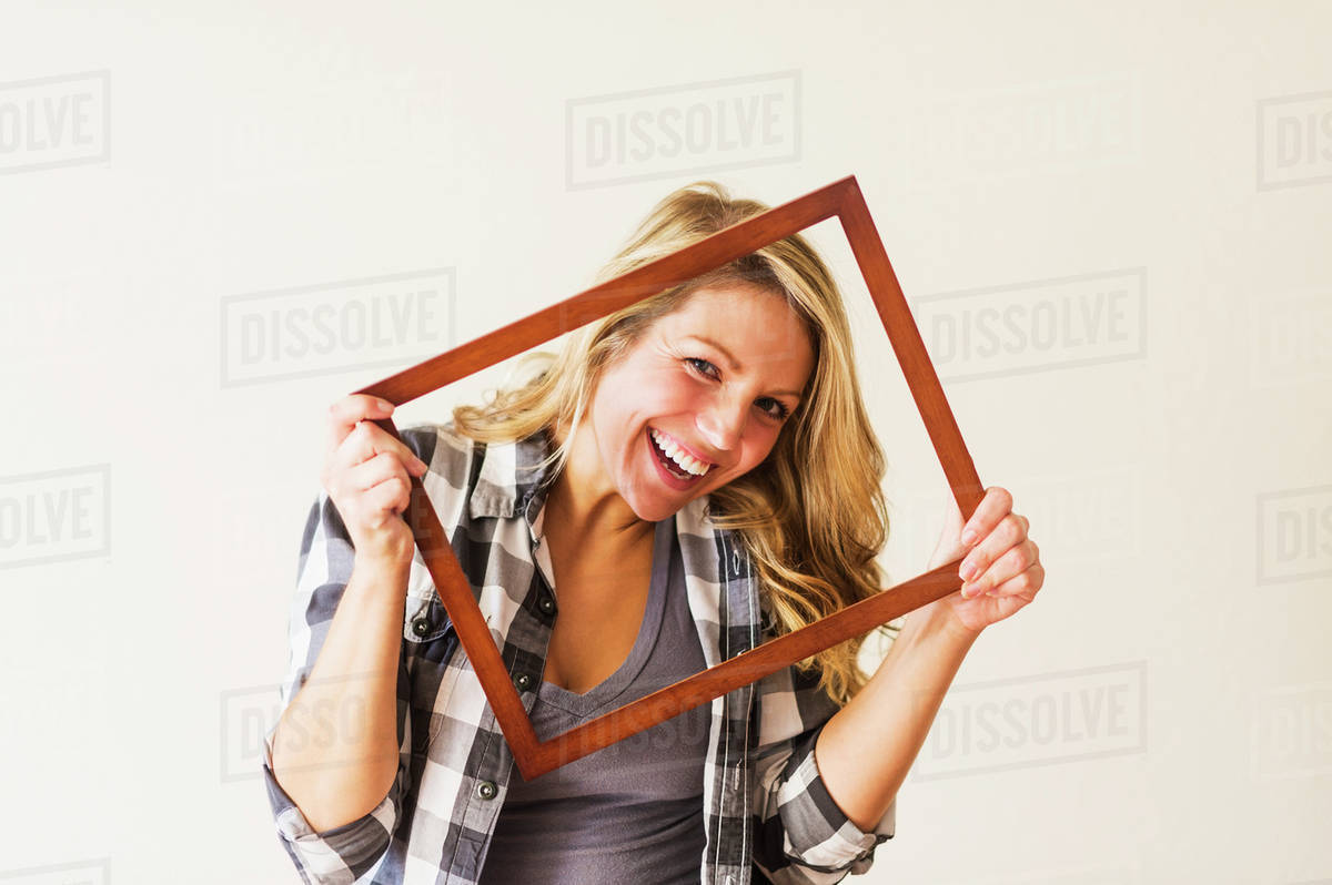 Portrait of woman holding picture frame - Stock Photo - Dissolve