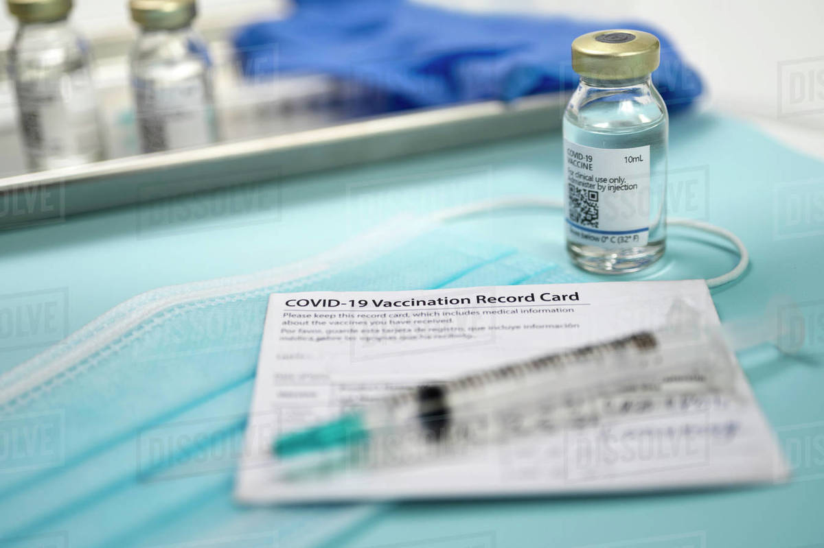Syringe on Covid-19 vaccination record card and vials on tray - Stock ...