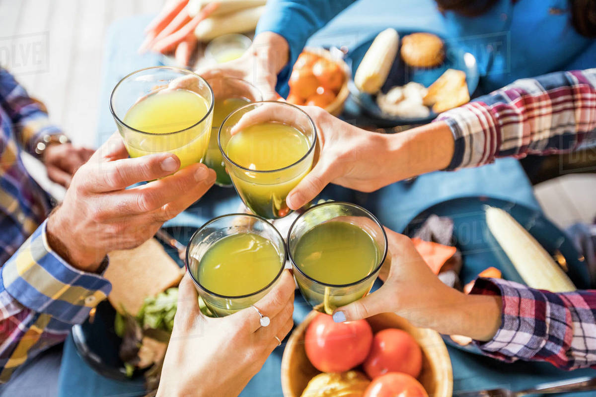 Family with children (10-11, 12-13, 16-17) raising toast with orange ...