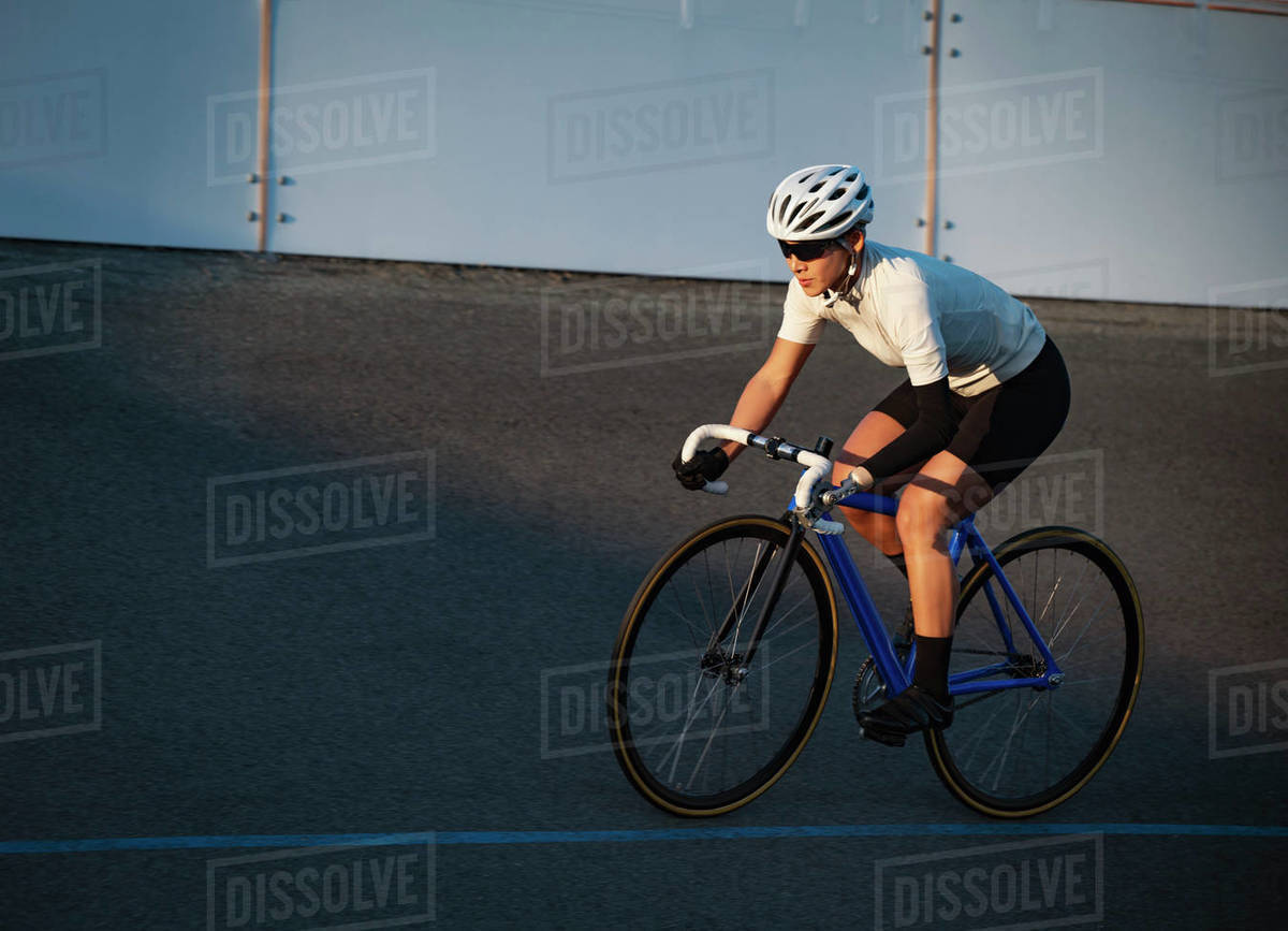 Athletic woman with prosthetic arm riding bicycle - Stock Photo - Dissolve
